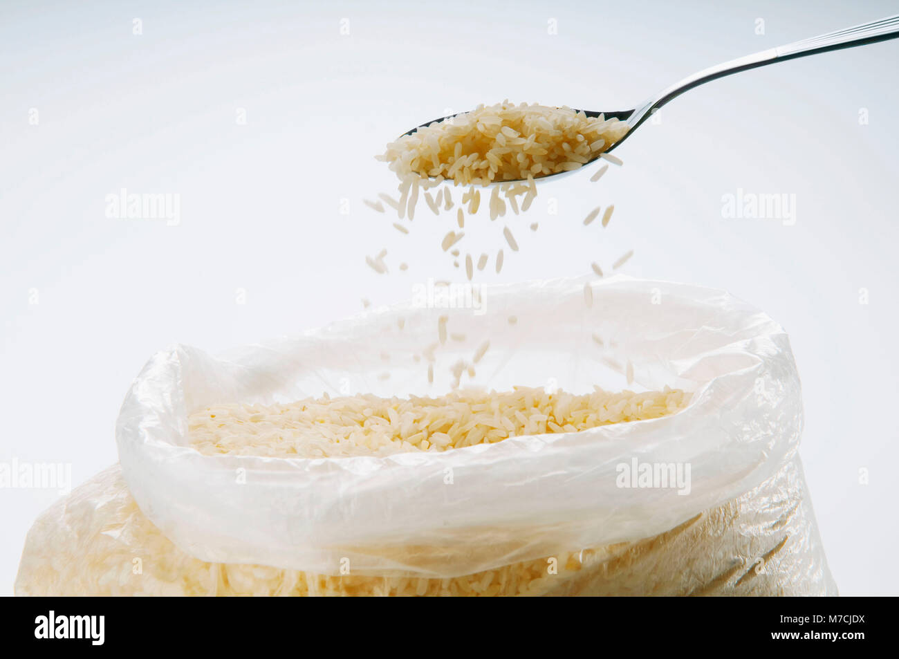 Rice being poured into a plastic bag from a spoon Stock Photo - Alamy