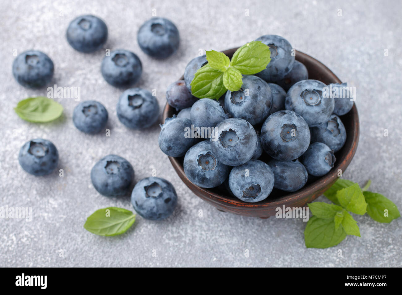Fresh organic blueberries in a clay bowl. Juicy berry and mint leaves ...