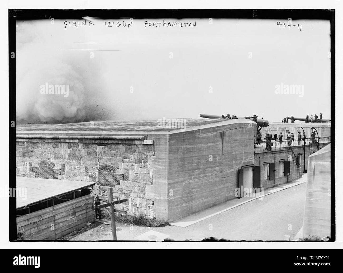 Photograph showing soldiers firing a 12-foot cannon at Fort Hamilton, a ...