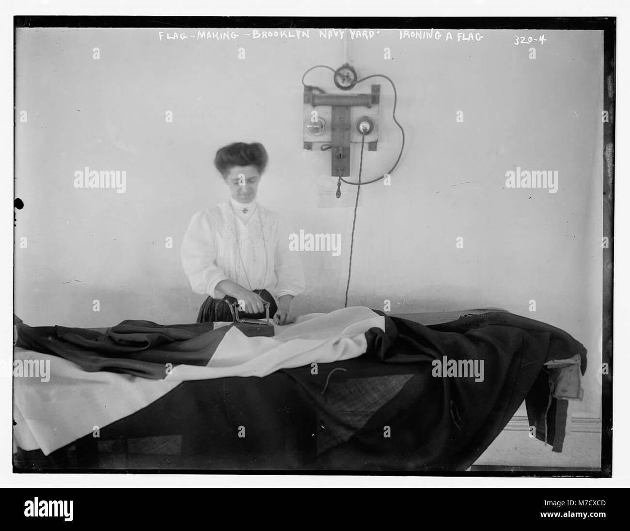 A photograph showing workers at the Brooklyn Navy Yard ironing a flag ...
