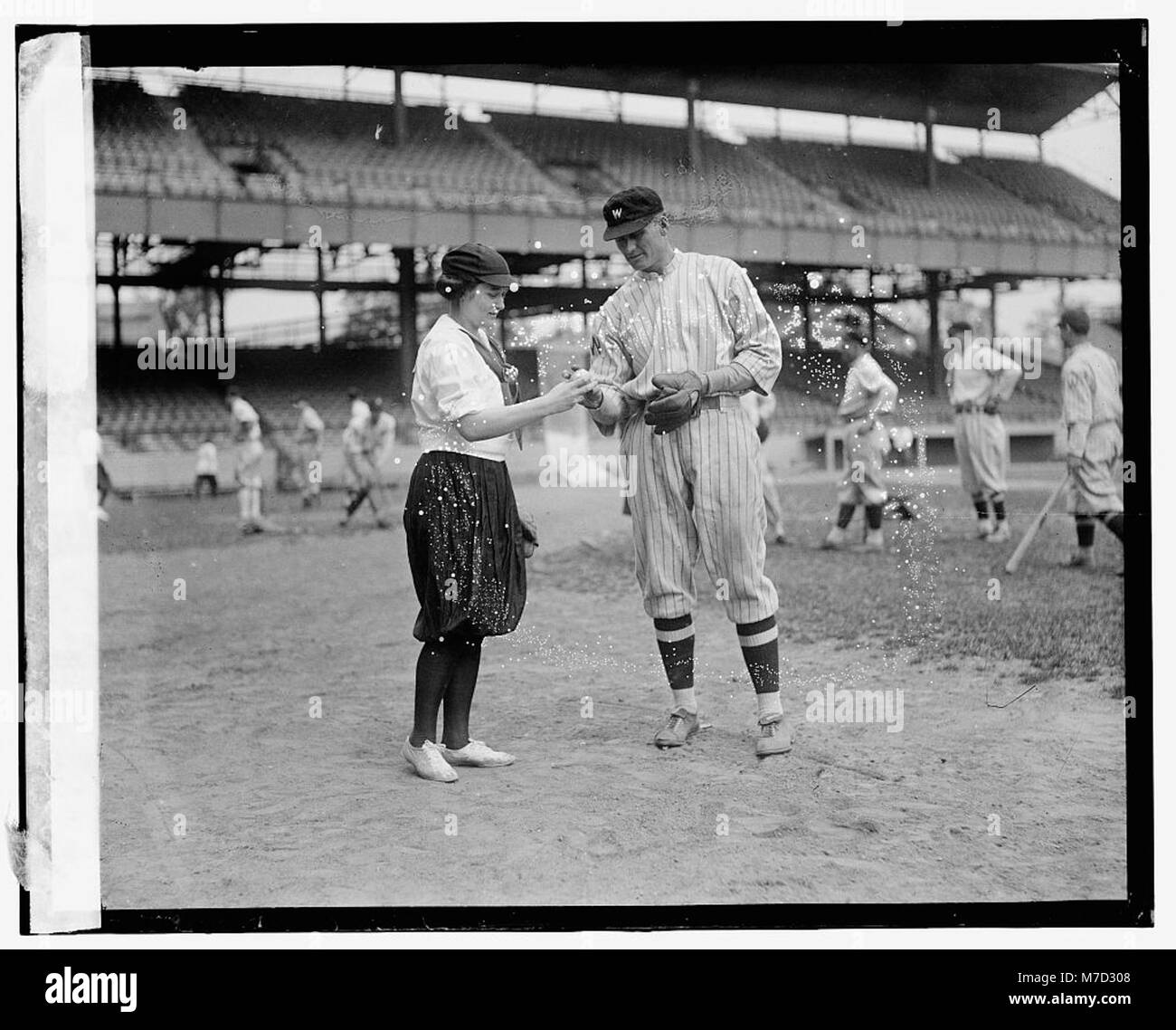 This photograph depicts a girls’ baseball game, highlighting the ...