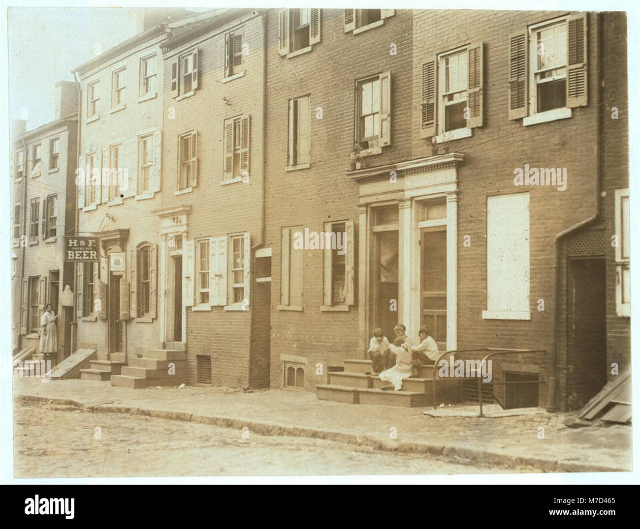 A photograph of a group of children playing on the stoop of a house ...