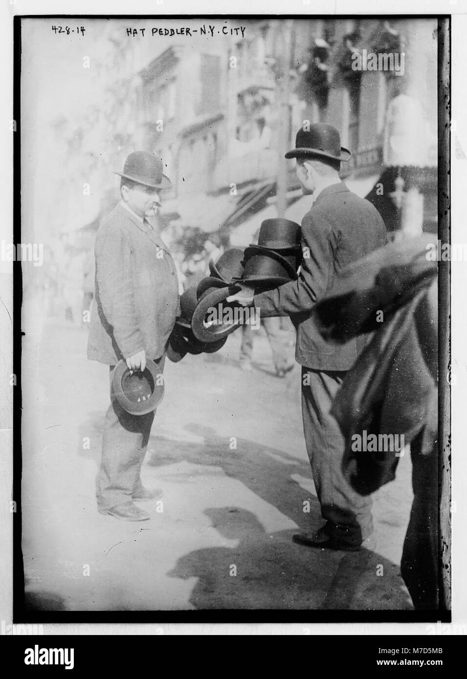 This photograph shows a hat peddler interacting with a prospective ...