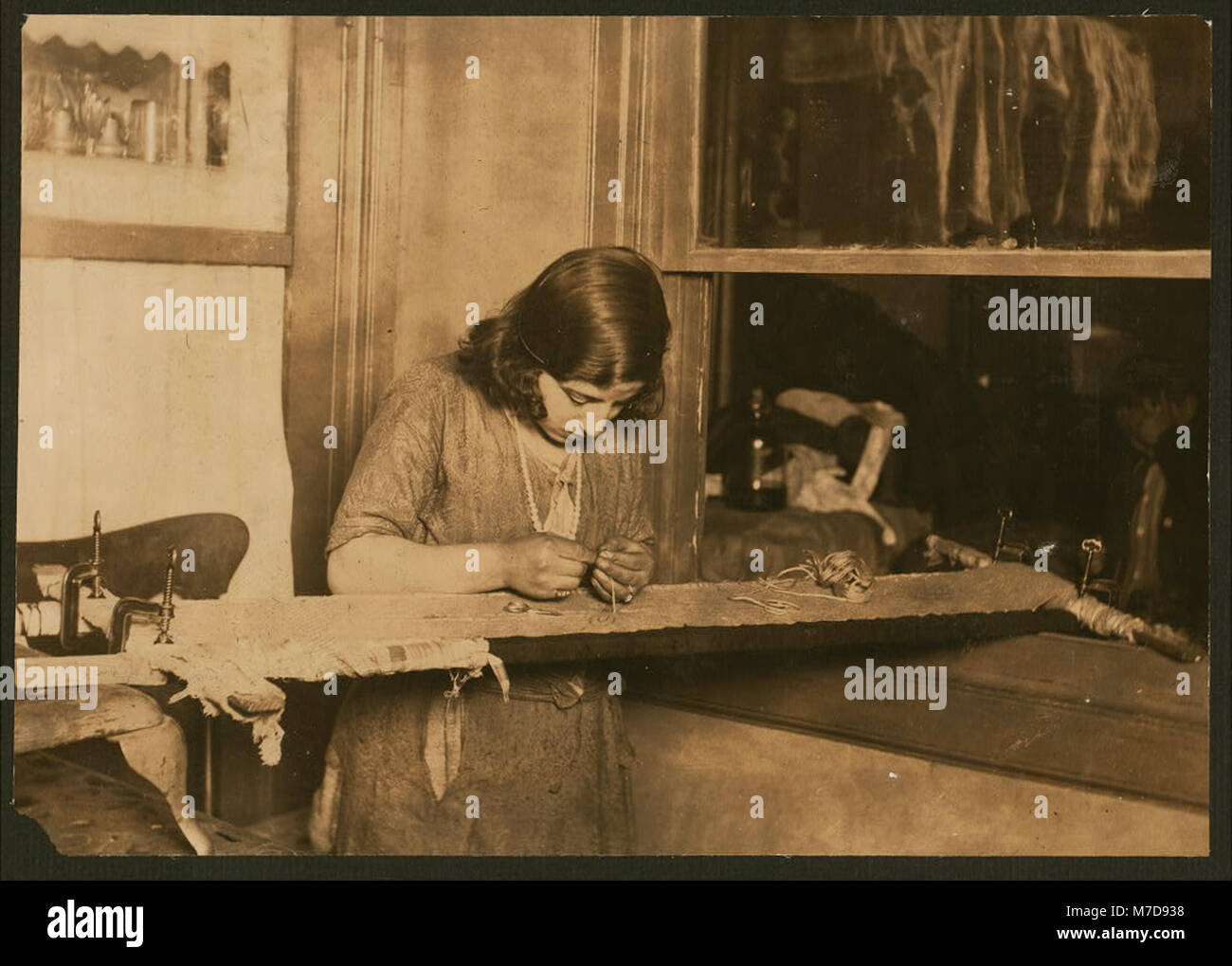 A 13-year-old girl is seen working at embroidery in a poorly lit room ...