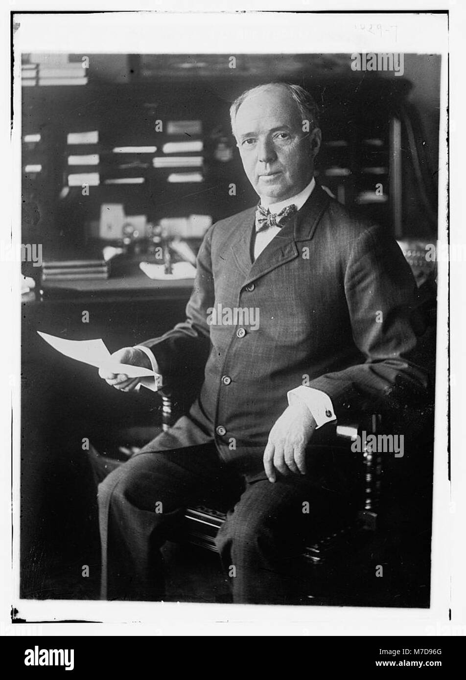 A seated portrait of J.D. Archbold, holding a document, emphasizing his ...