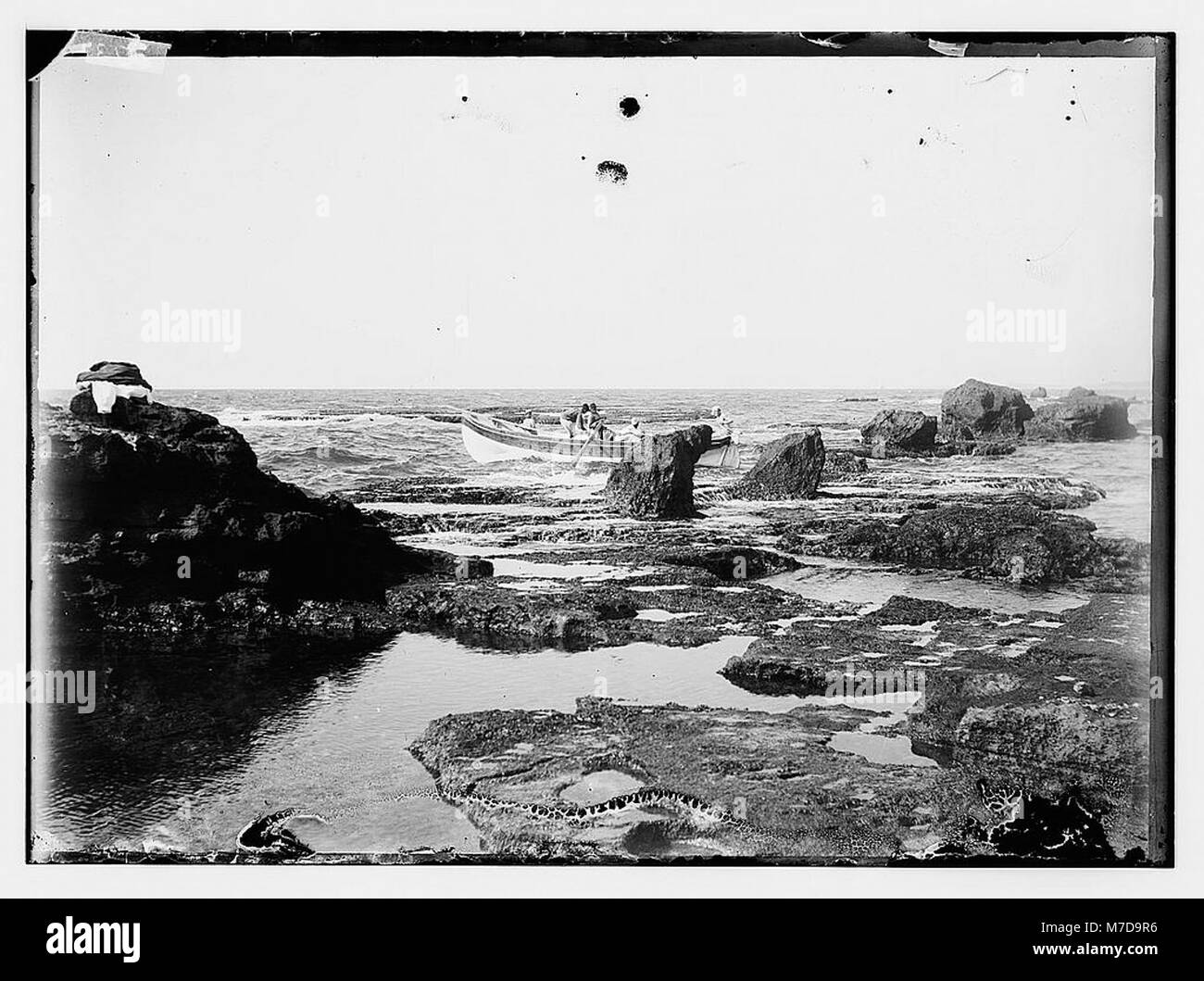 A historical image showing a boat navigating through rocky waters near ...