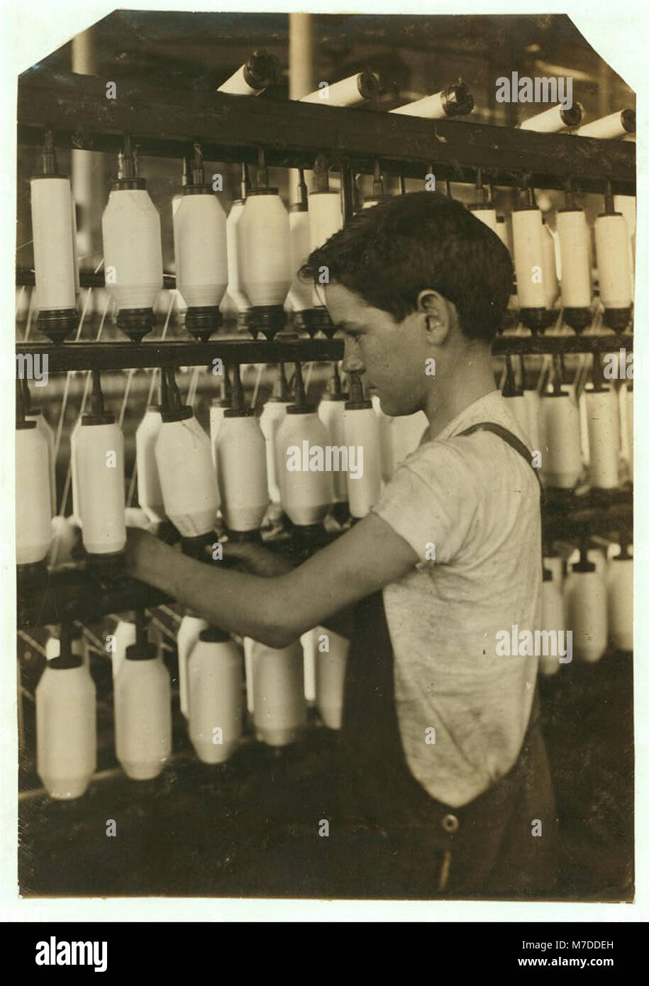 A historical image of a young boy working in a mule spinning room ...