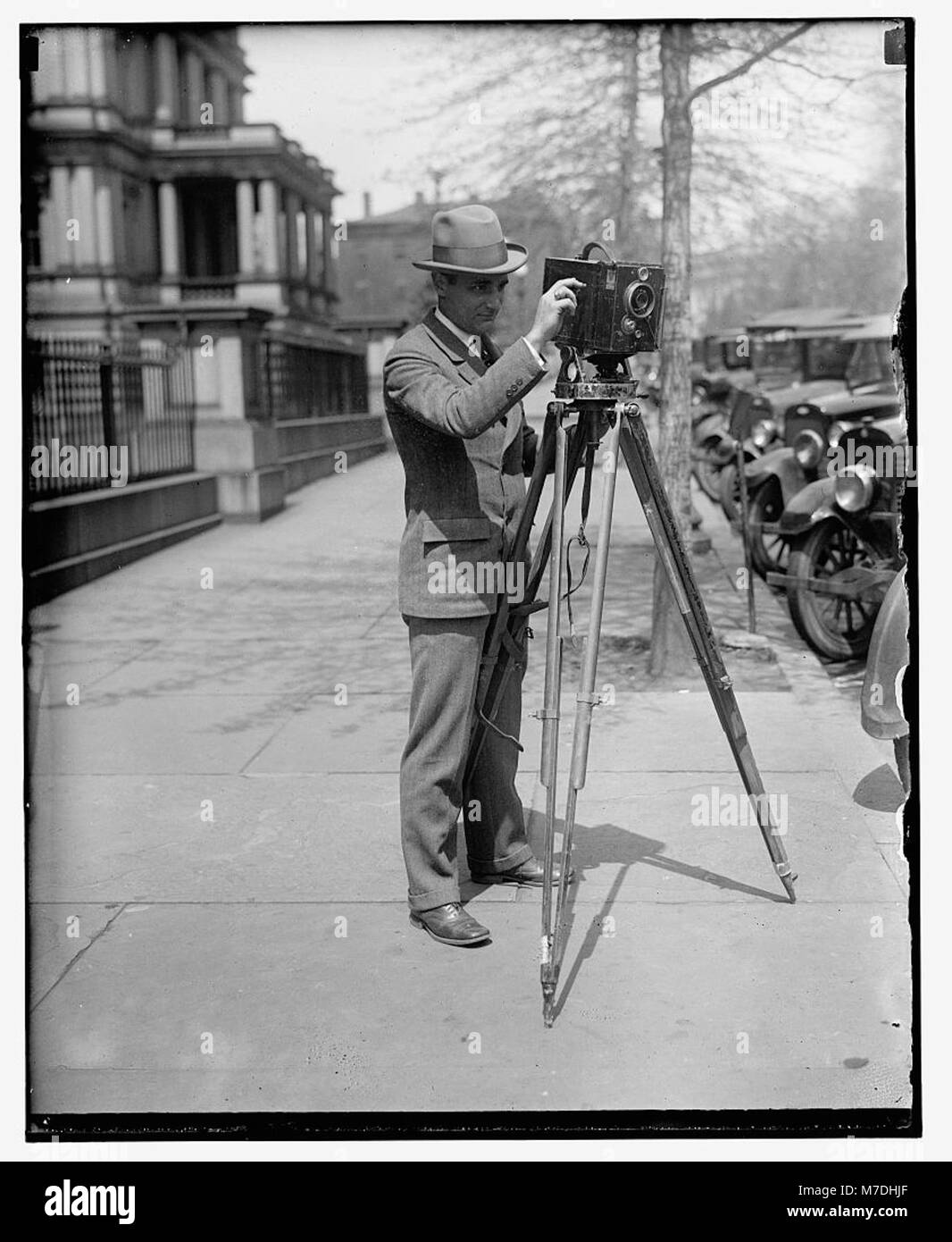 A historical photograph of a man using a motion picture camera, likely ...