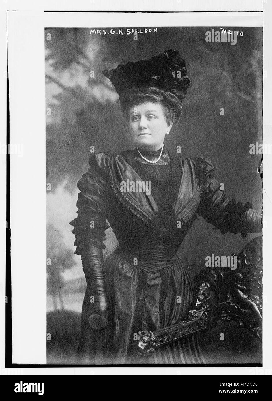 A portrait of Mrs. G.R. Sheldon, standing beside a chair, capturing her ...