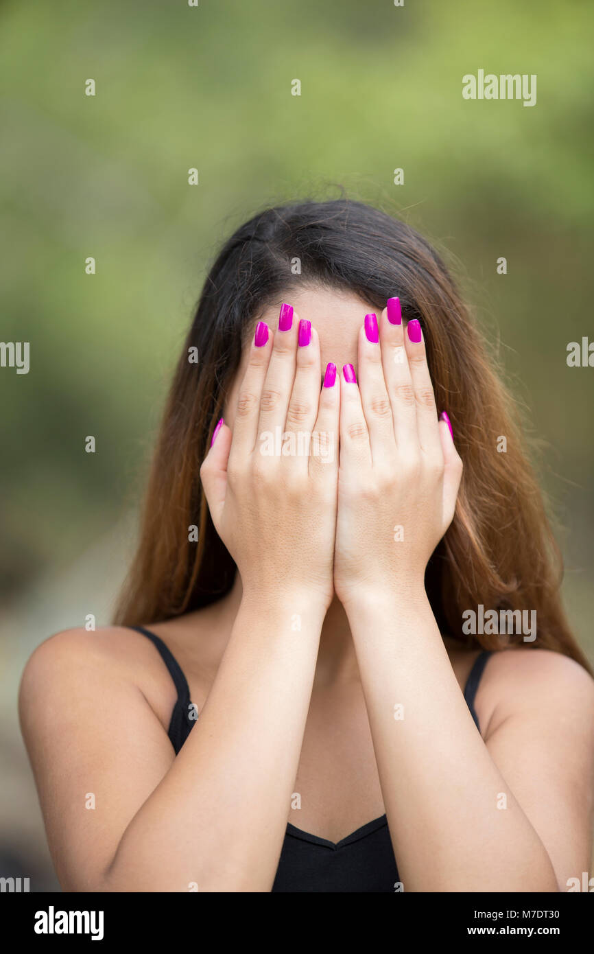 Young woman hiding her face with her hands Stock Photo - Alamy