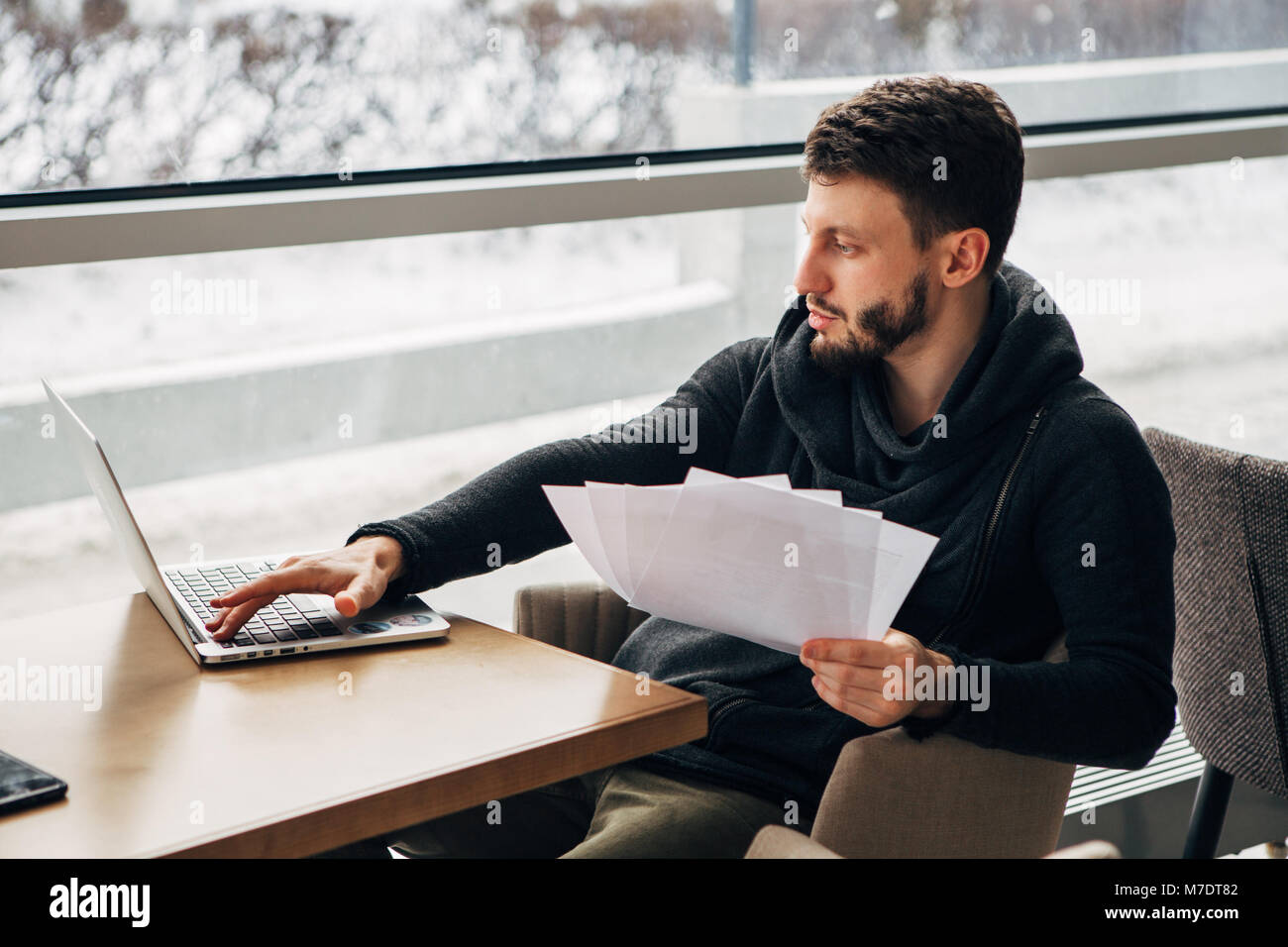 Young man sitting at the cafe and using laptop Stock Photo - Alamy