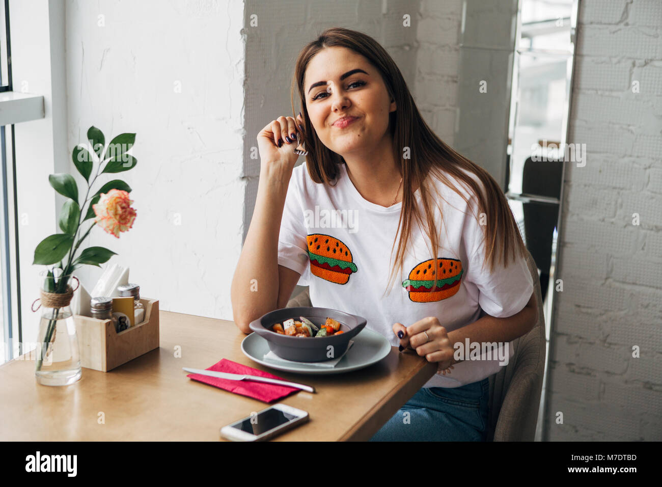 beautiful girl is having lunch in a cafe at a wooden table Stock Photo ...