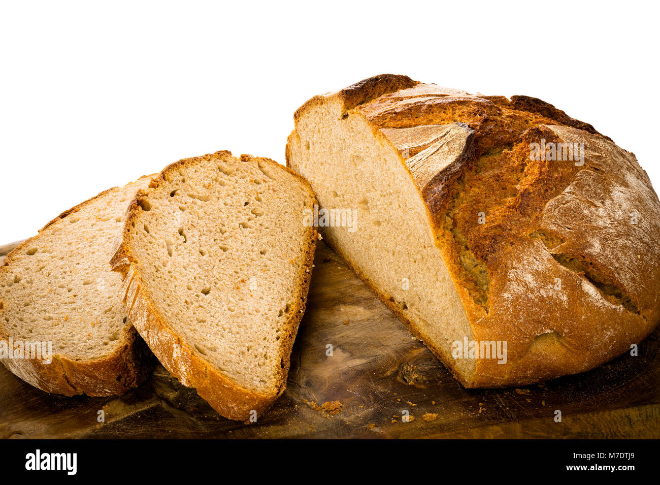 Loaf of rustic german bread, partly sliced, on wooden breadboard ...