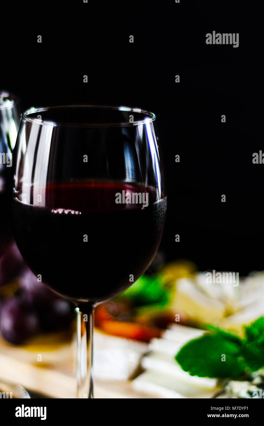 Red wine and set of different cheeses on a wooden board, delicious ...