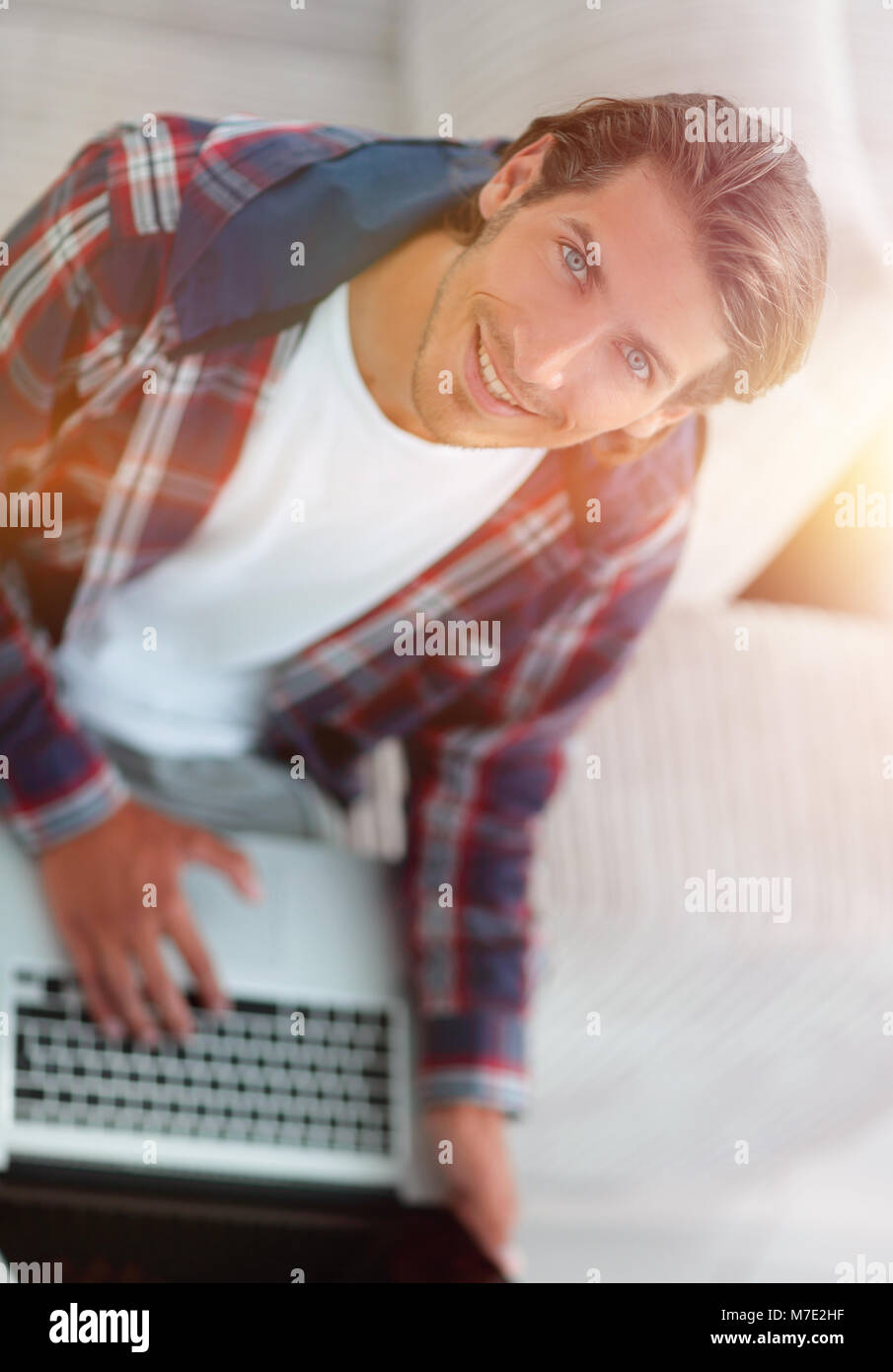 young man working on laptop and looking at camera. view from above ...