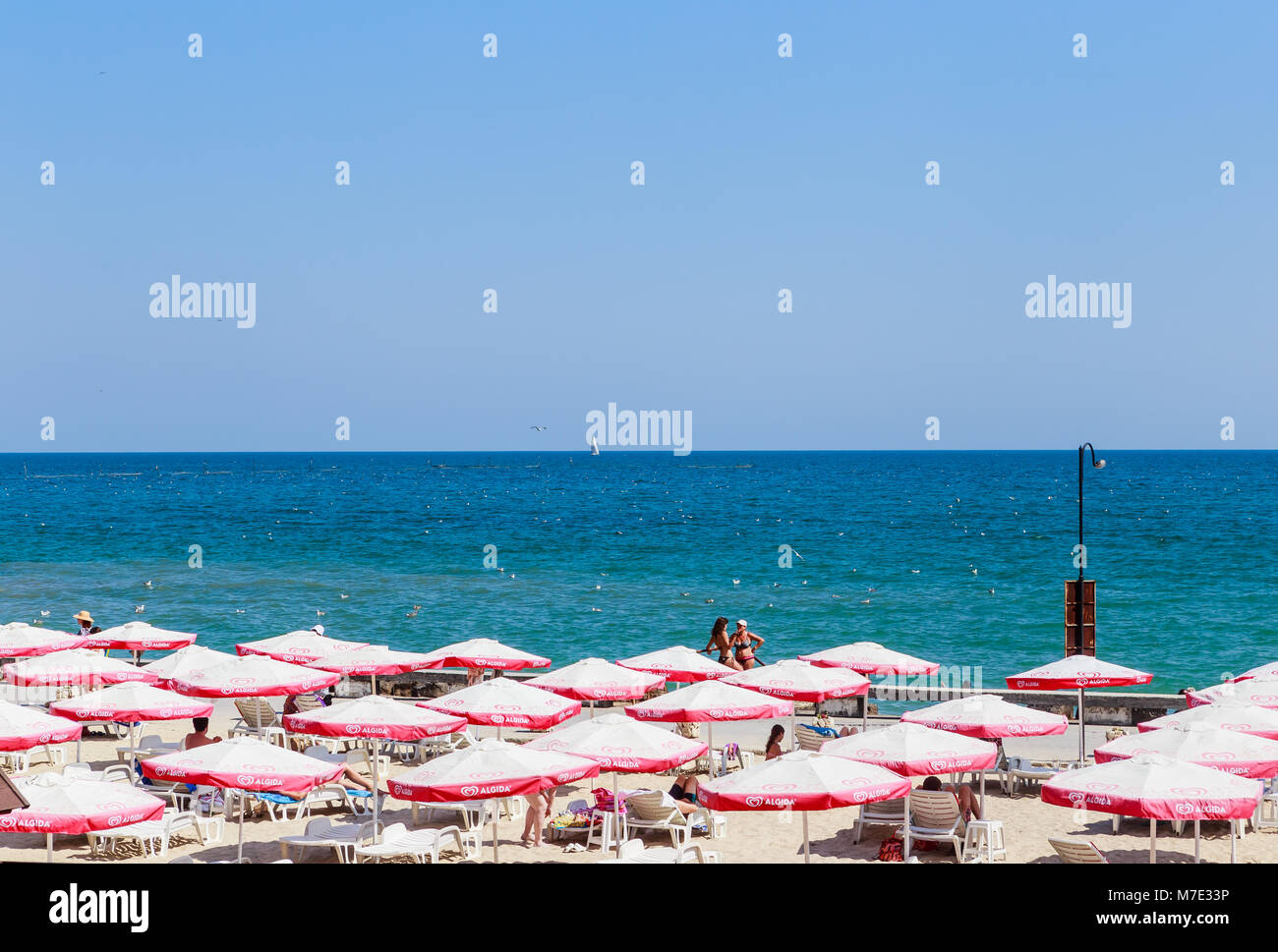 The Balchik seaside, beach with sands, sun umbrellas and blue water ...