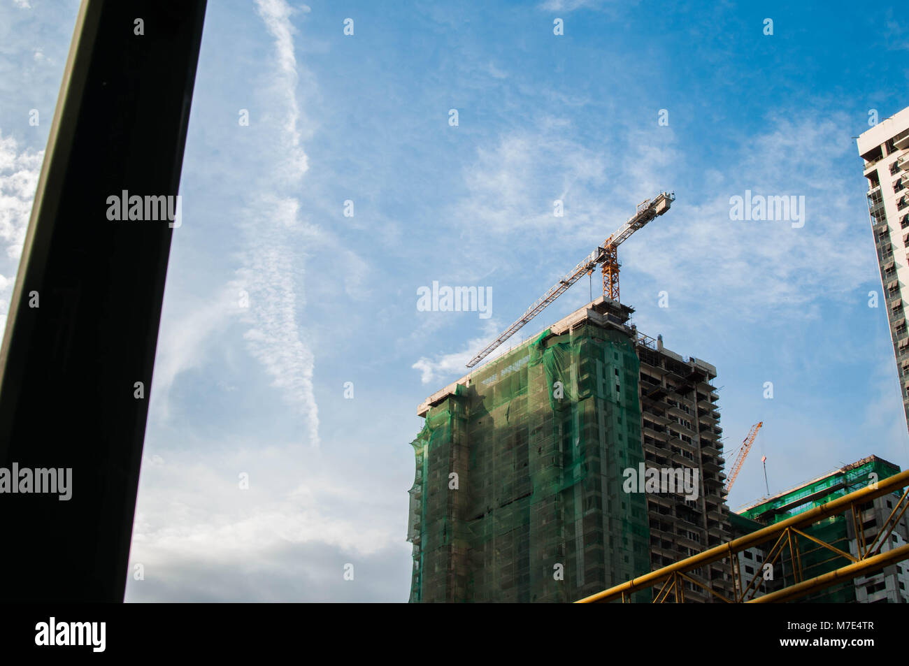 Construction crane on top of a unfinished building against blue sky ...