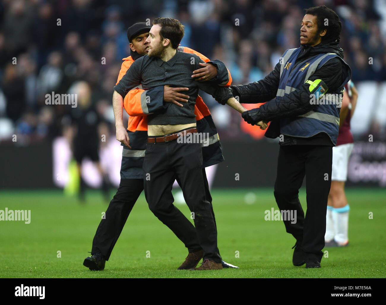 A Pitch invader is confronted by security during the Premier League ...