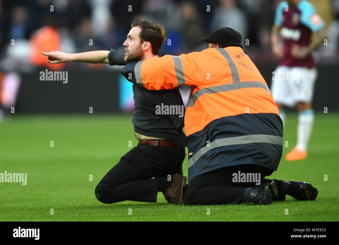 A Pitch invader is confronted by security during the Premier League ...