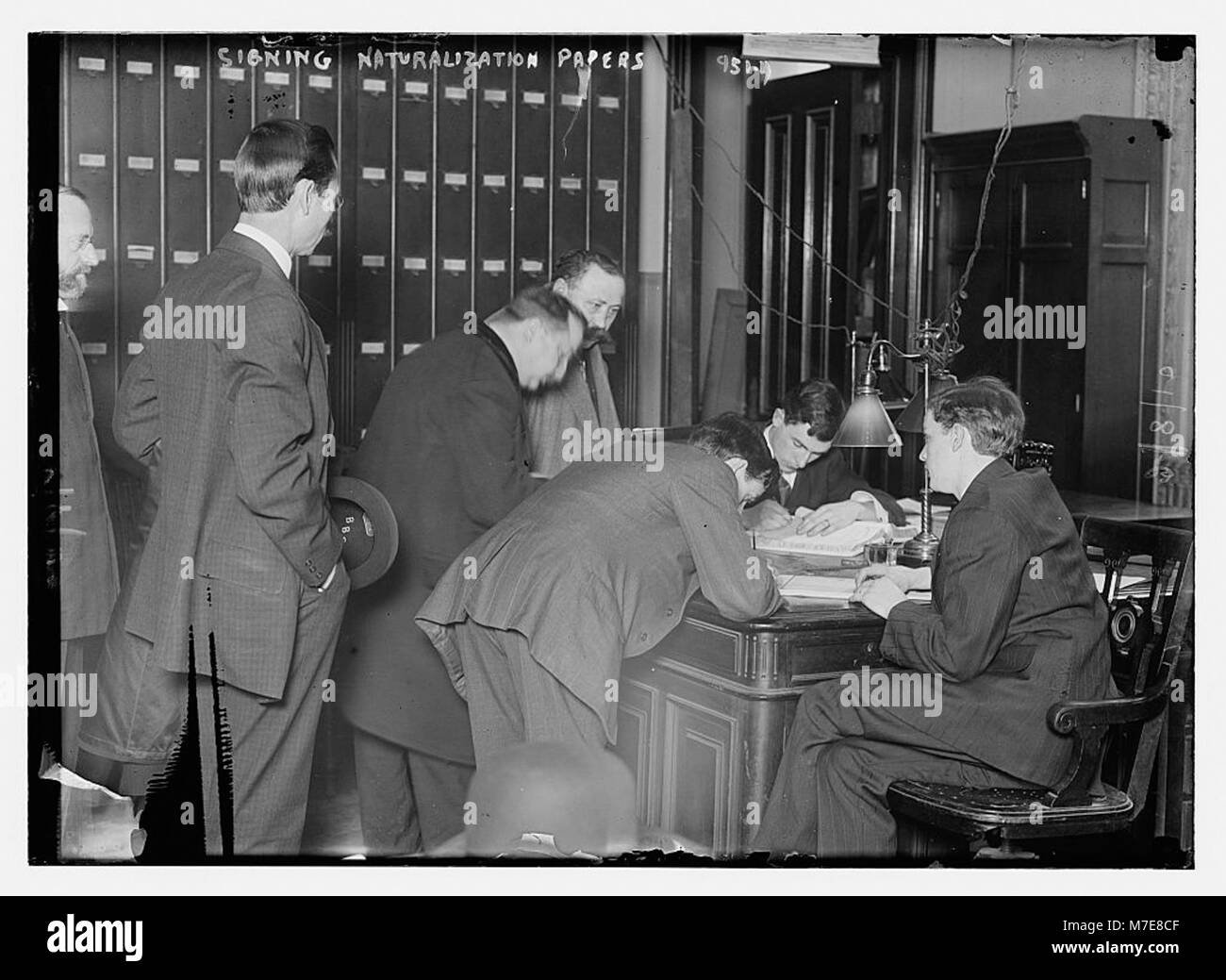 An image showing new citizens signing their naturalization papers in a ...