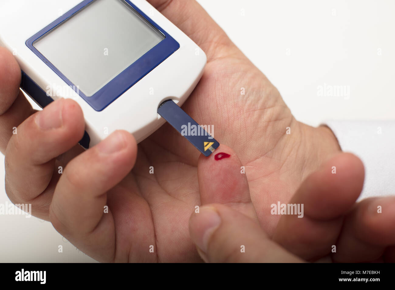 Diabetic taking a blood sample from his finger using a small portable ...