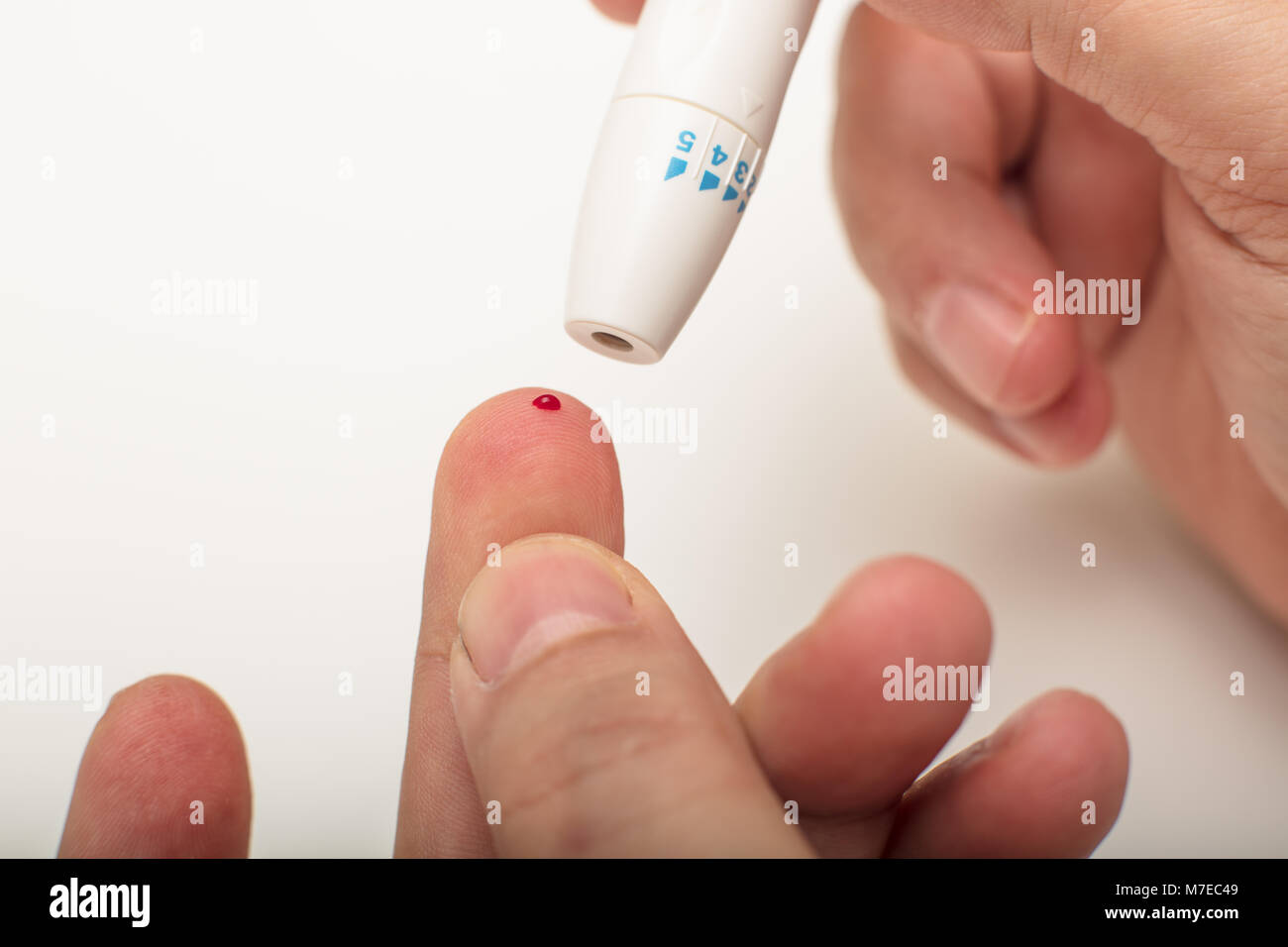 Diabetic using a lancet to take a blood sample by pricking the tip of ...