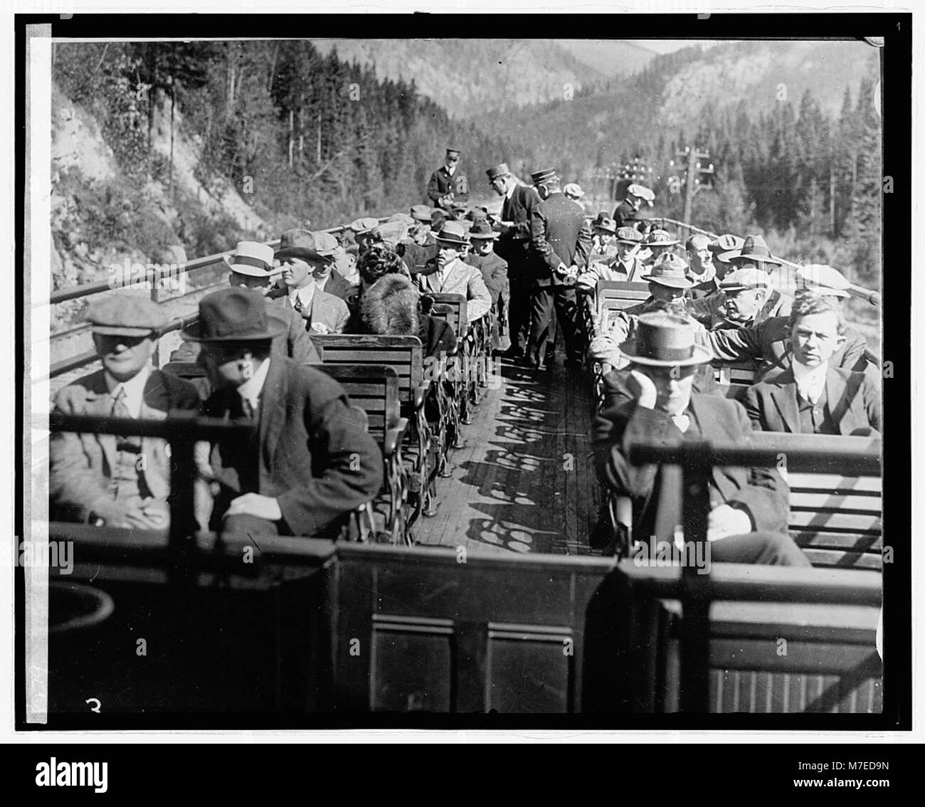 This image shows passengers traveling on the roof deck of a train as it ...