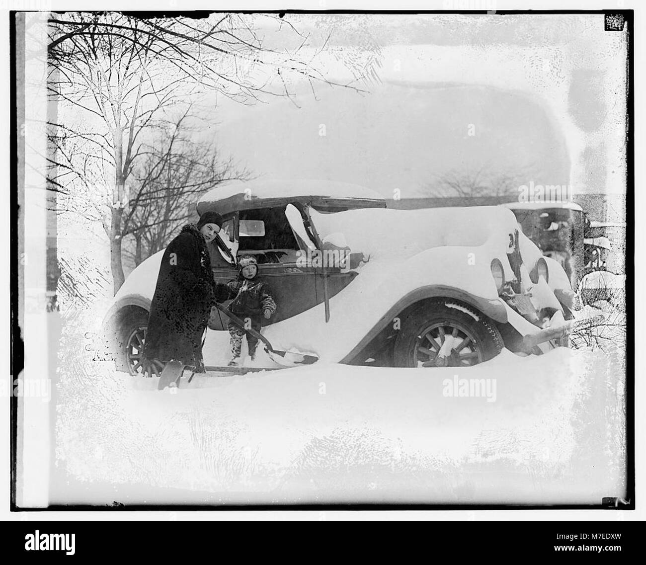 A person clears an automobile covered in snow, capturing the challenges ...