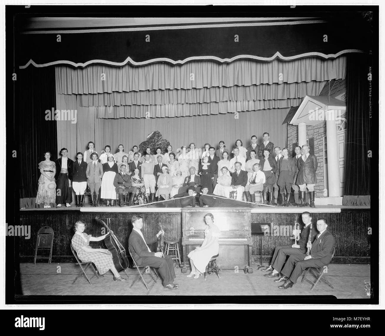 This photograph features a stage with a group of performers, capturing ...
