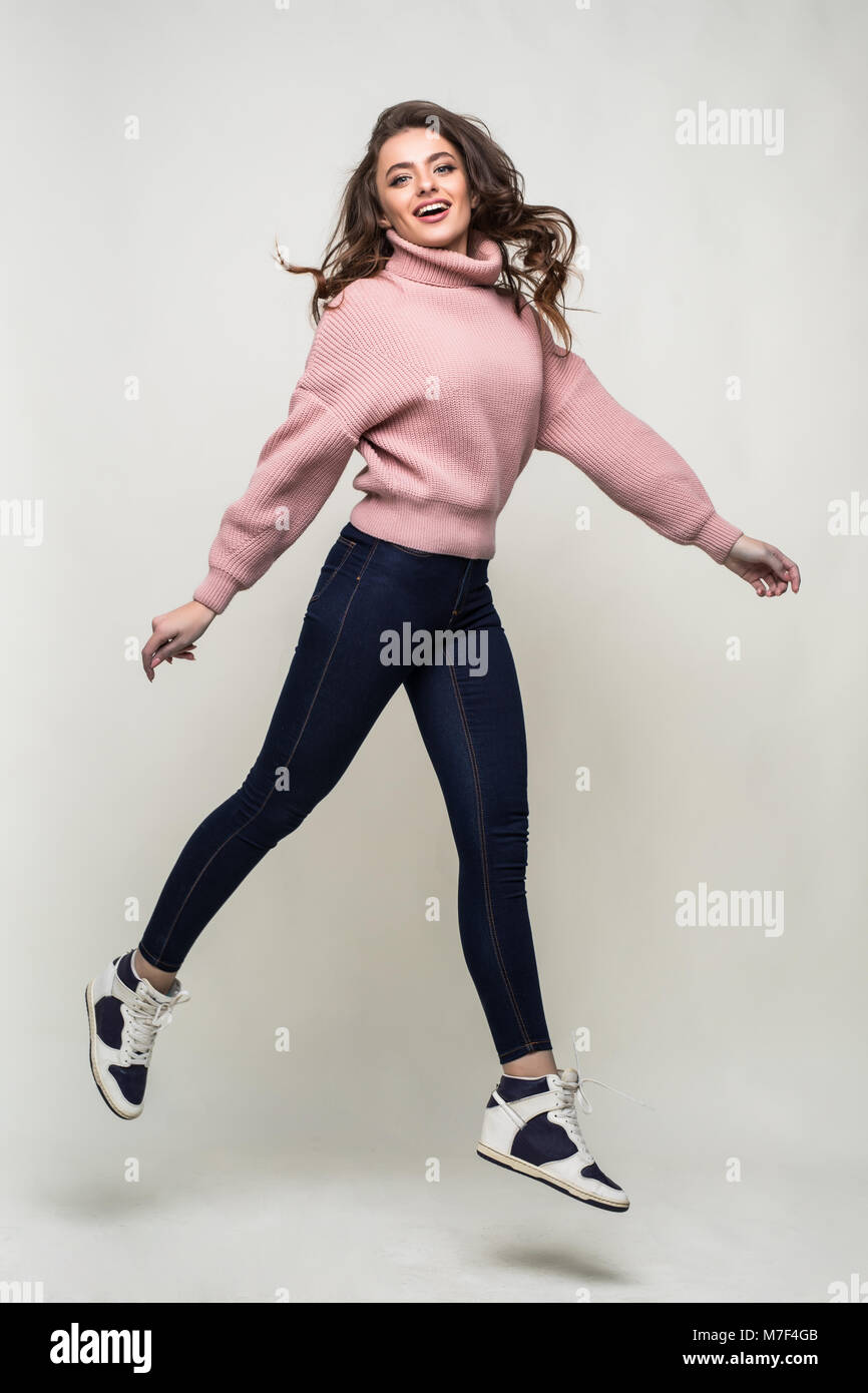Full length portrait of a casual young woman jumping and looking at ...