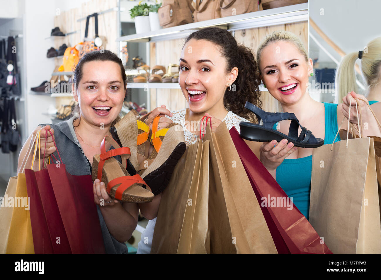 Three young cheerful girls shopping together and chatting Stock Photo ...