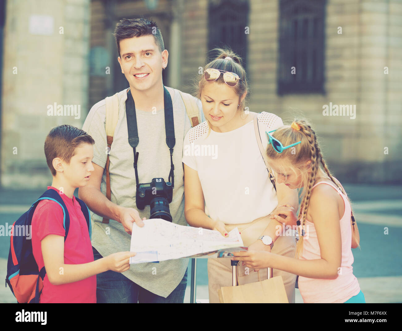 Cheerful parents with two kids traveling together searching location on ...