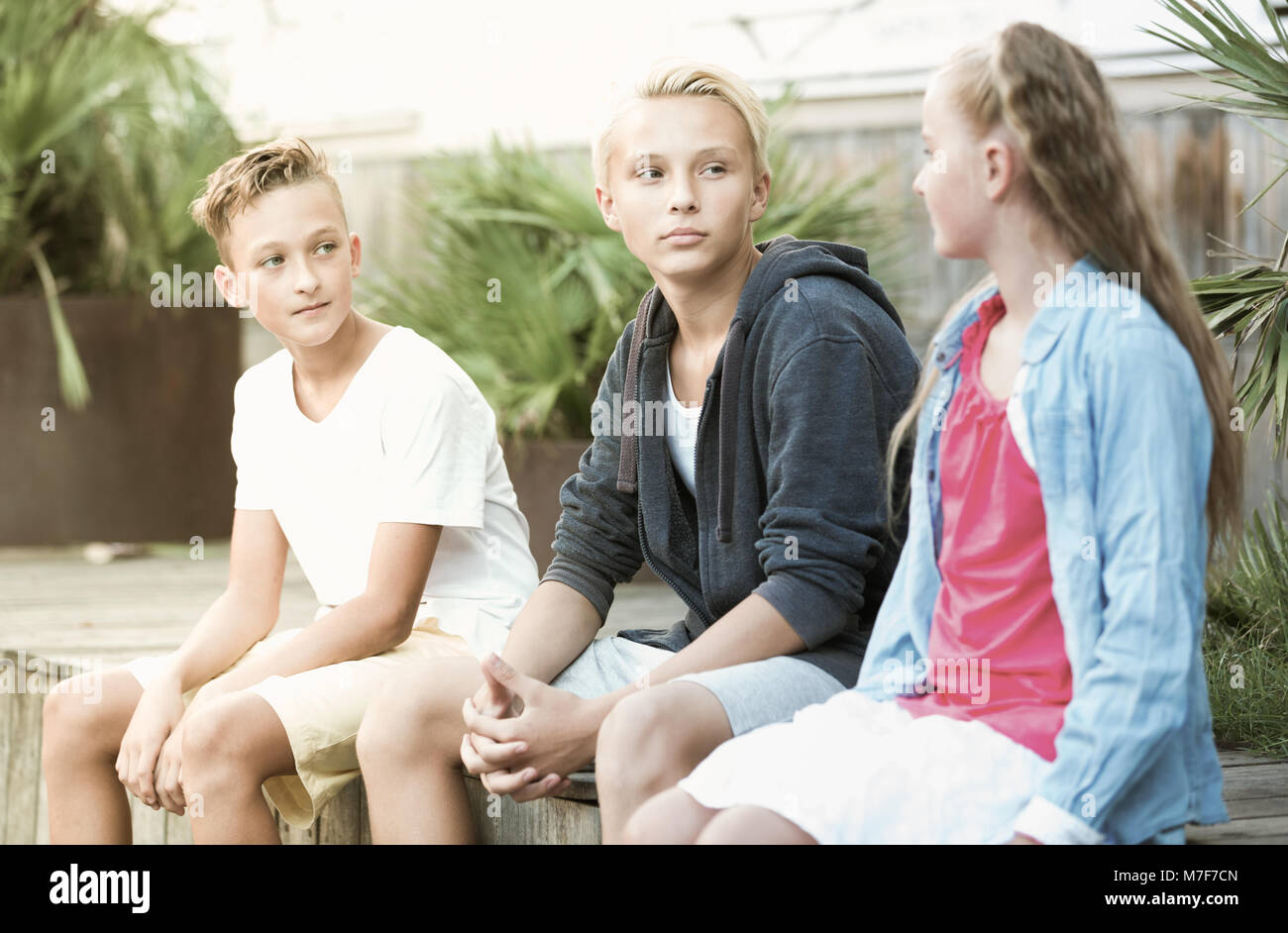 Group of positive children relaxing and chatting in town square garden ...