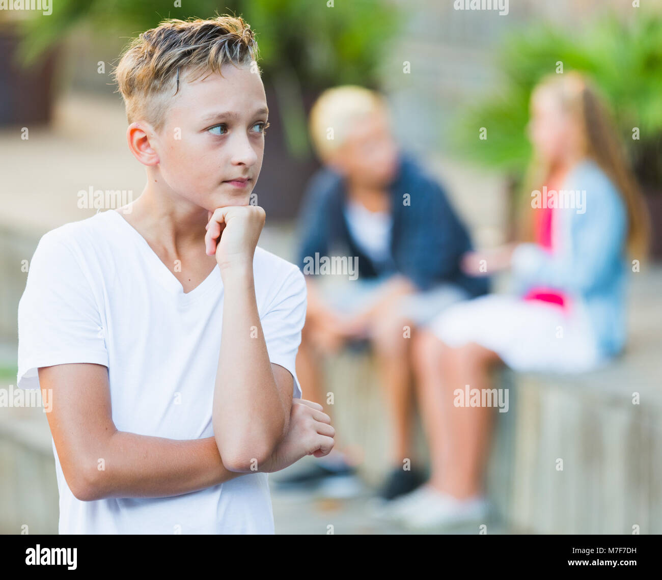 Portrait of sad boy standing apart having problems in relationship with ...