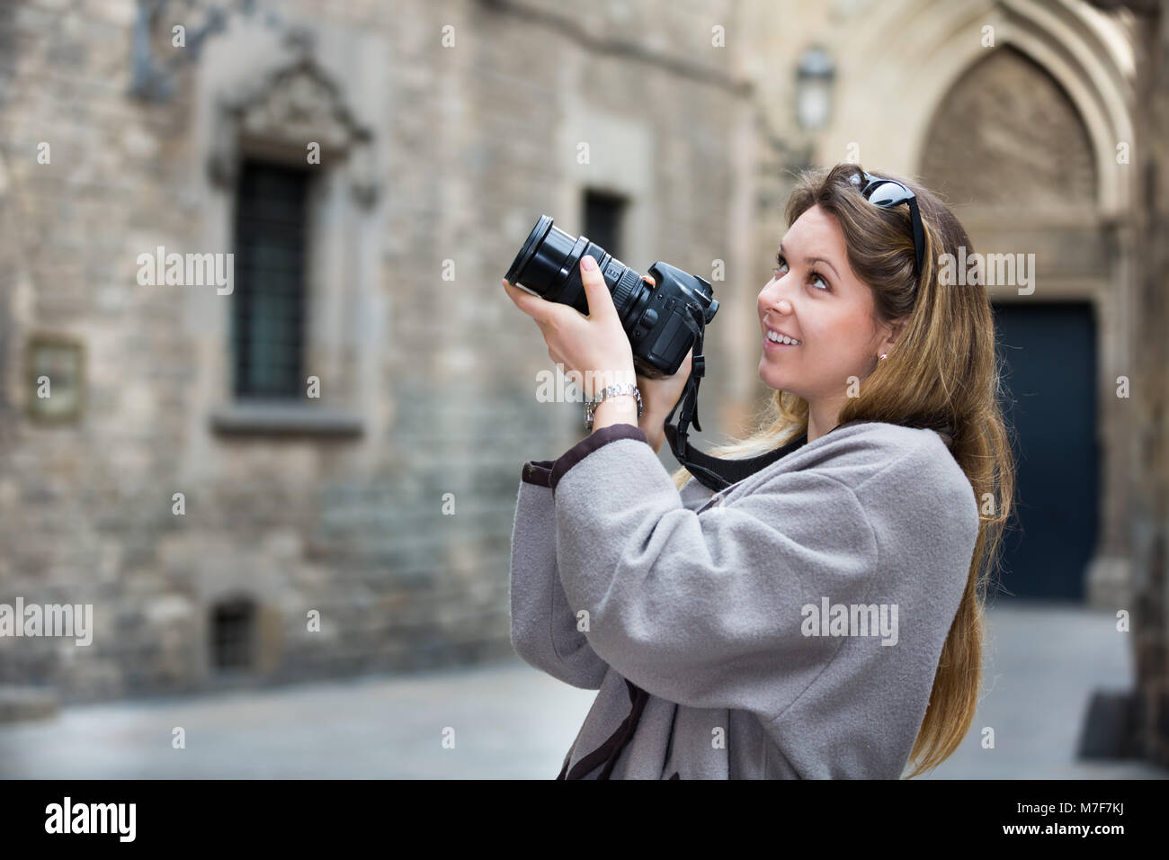 Young cheerful woman with camera looking curious and taking the ...