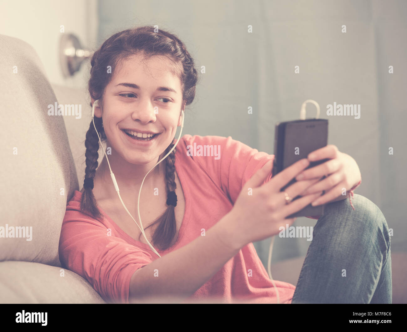 Young girl checking her phone and listening to music at home Stock ...