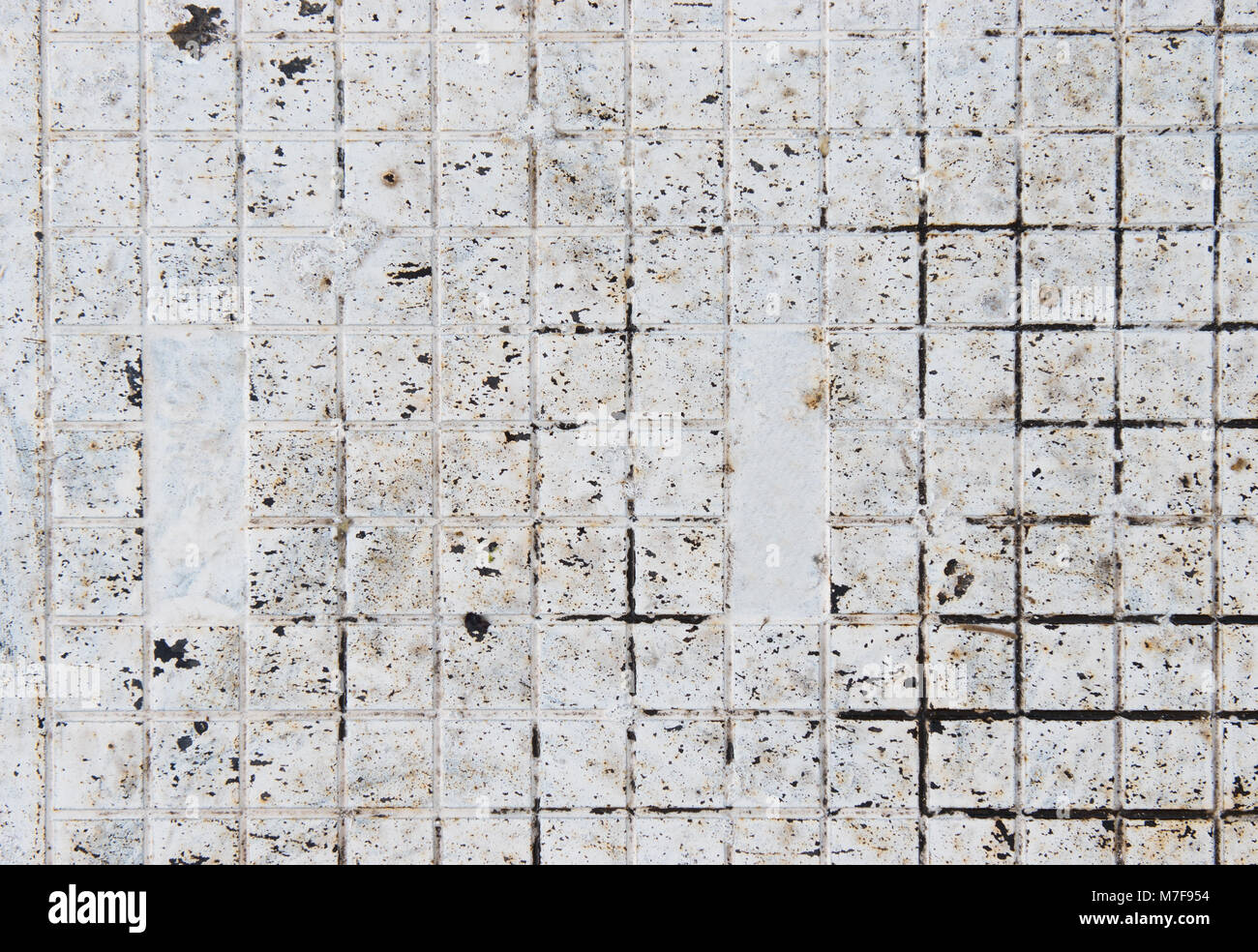 Small white metal square tiles covered with dirt. White background made ...