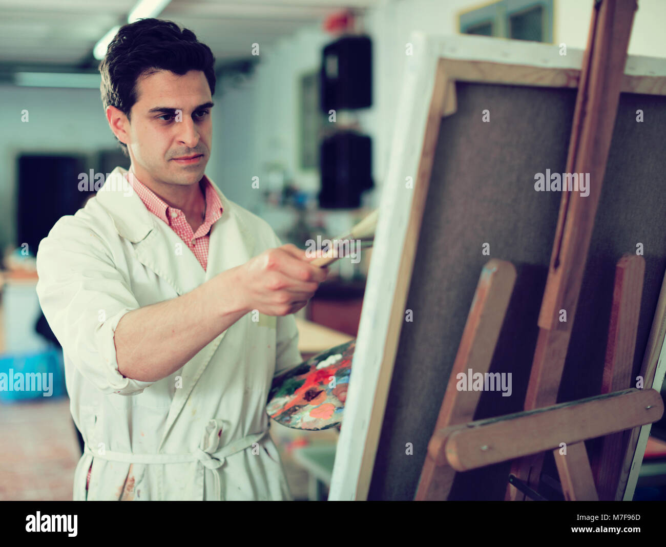Happy art painter holding artist palette and painting on canvas Stock ...