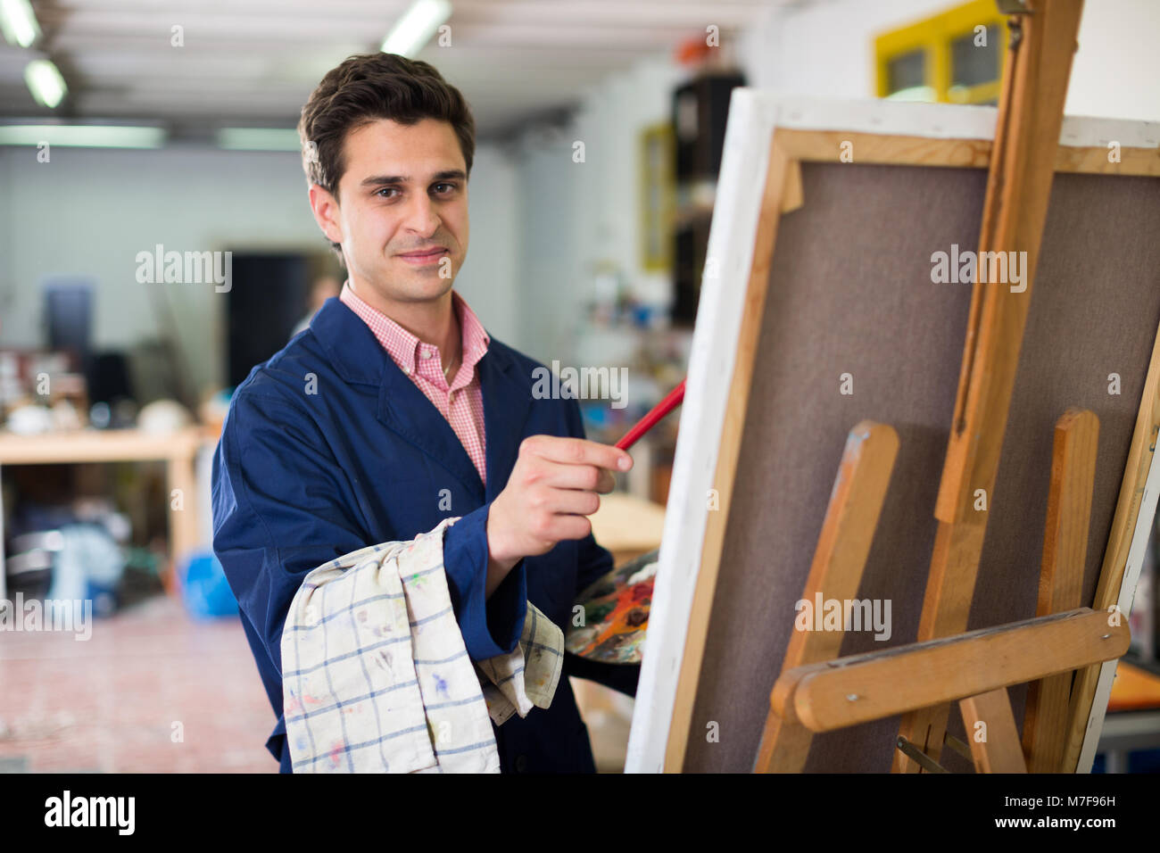 Happy art painter holding artist palette and painting on canvas Stock ...