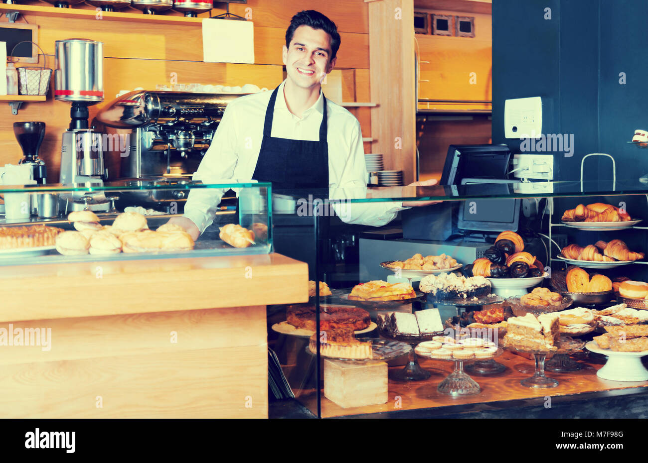 Happy man selling tarts and sweet pastry in coffee-house Stock Photo ...