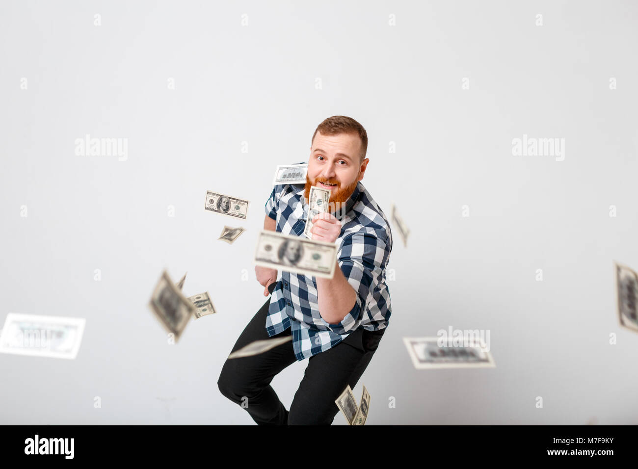 young handsome happy man with red beard standing under money rain of ...