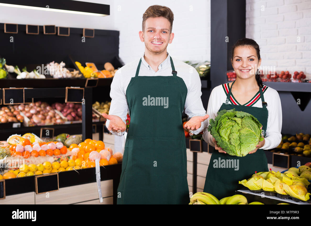 Smiling shopping assistants demonstrating assortment of grocery shop ...
