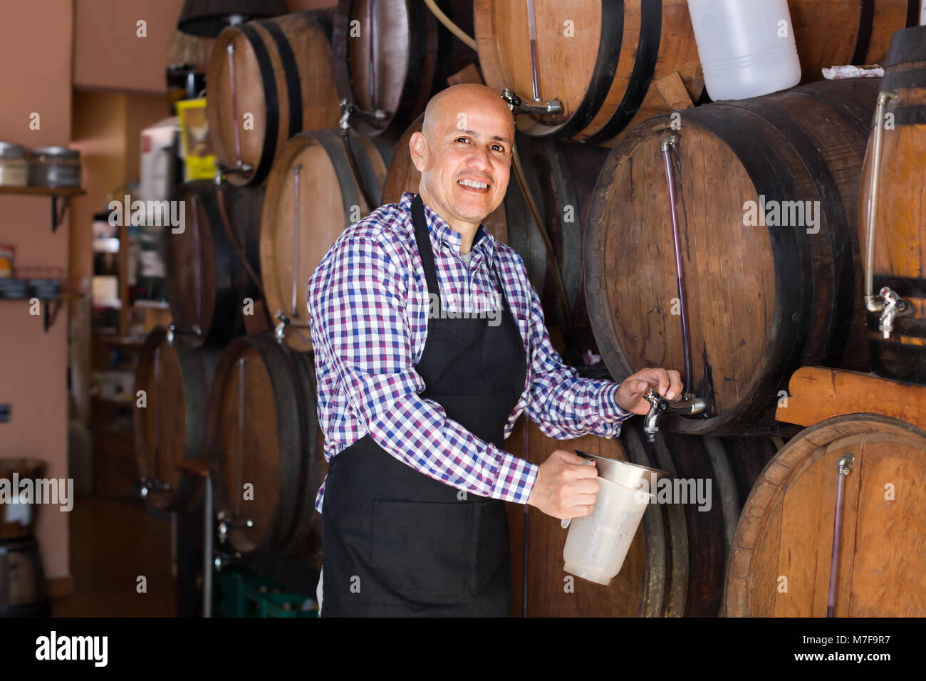 Happy man wine maker taking wine from wood in winery Stock Photo - Alamy