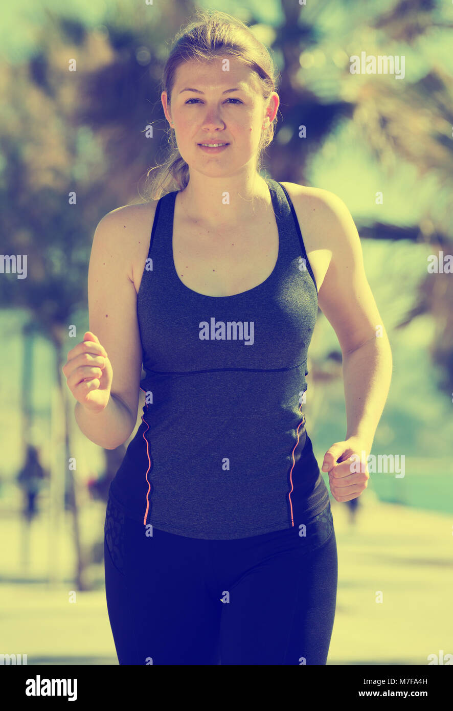Svelte woman jogging during outdoor workout on city seafront Stock ...