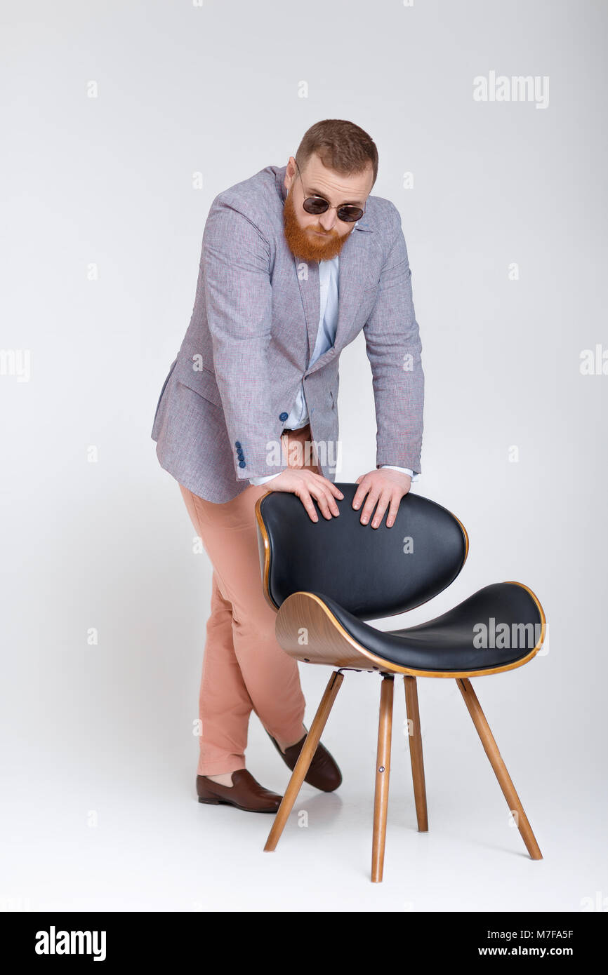 red-haired beard man in casual suit and sunglasses on gray background ...