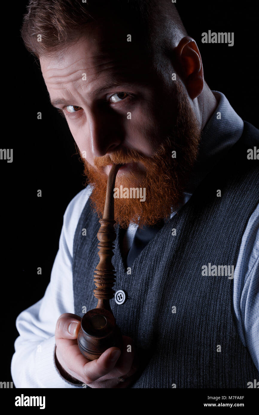 portrait of a red bearded man smoking a pipe on black background Stock ...