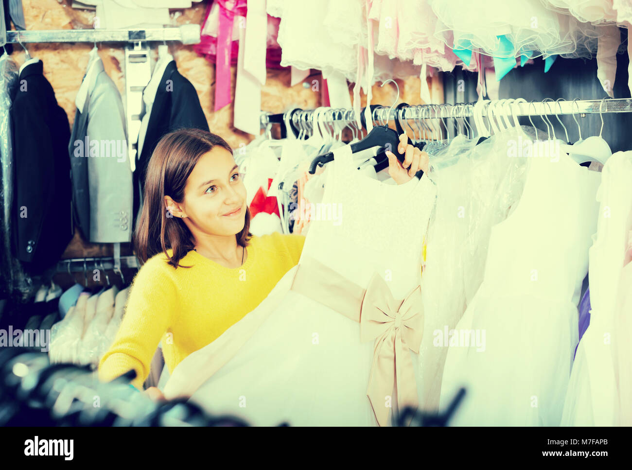 Cheerful girl choosing pretty dress in children’s cloths shop Stock ...
