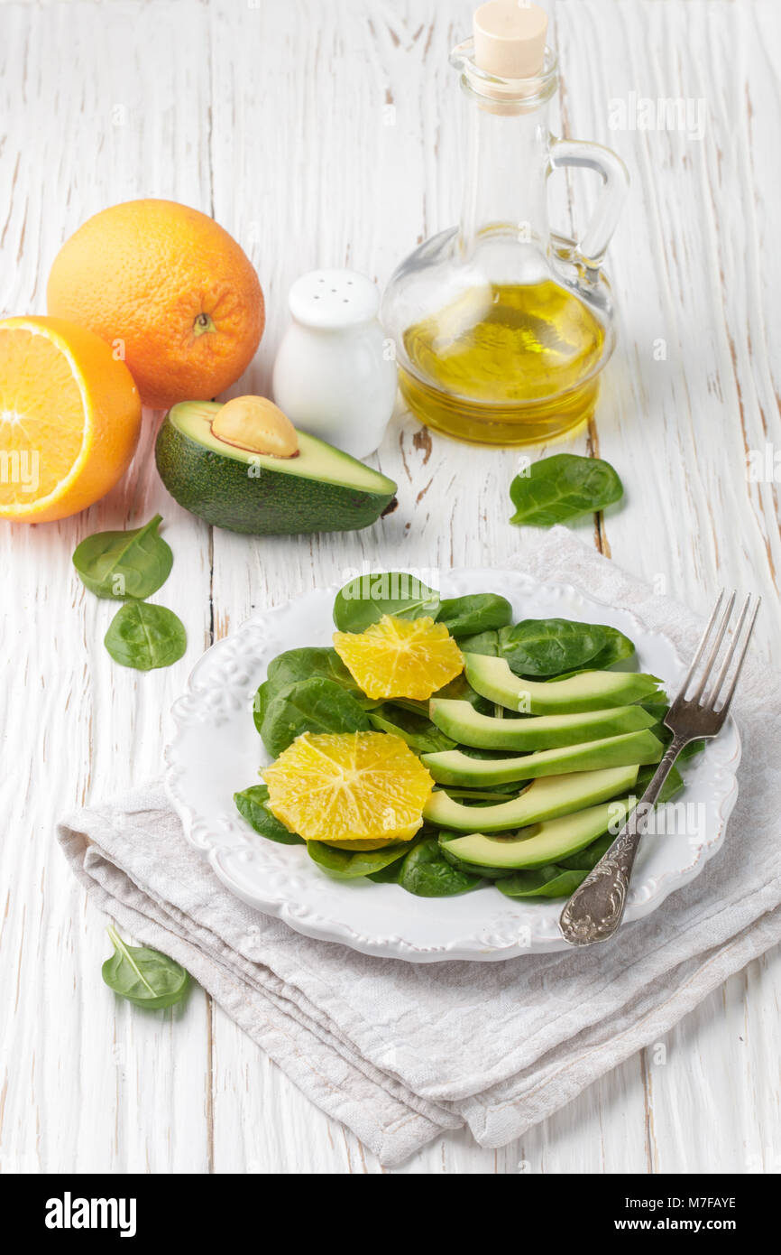 Organic avocado and spinach salad with orange and olive oil in a white ...