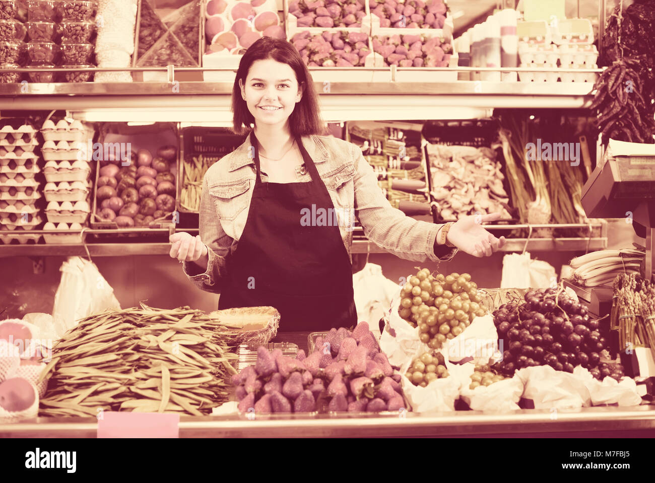 smiling female shopping assistant demonstrating assortment of grocery ...