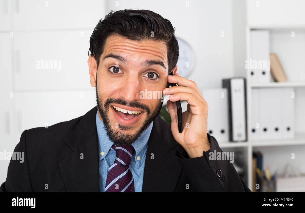 Excited adult man is talking phone with his partner in office Stock ...